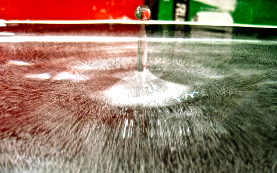 A droplet of water falling into a shallow pool of water rebounds into a ...