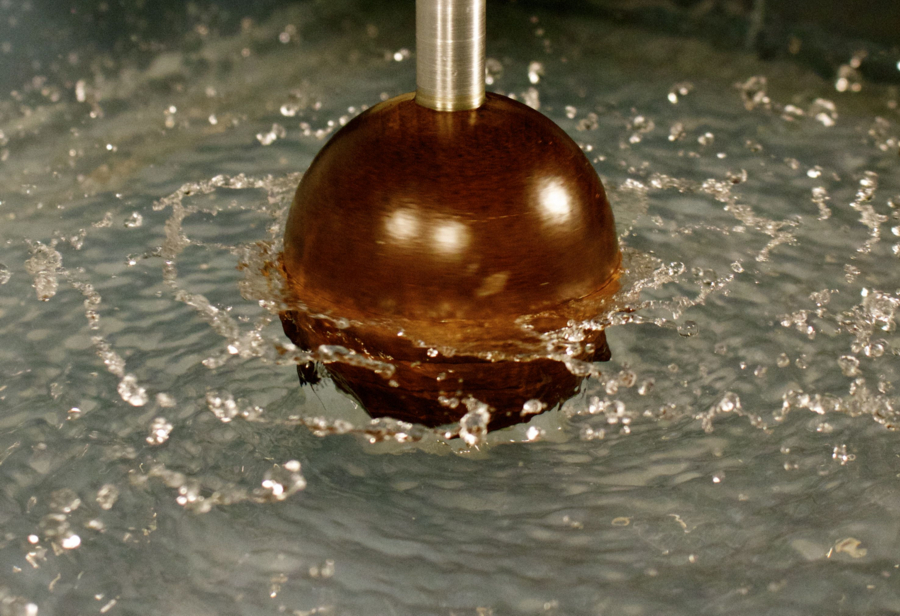 A sphere spinning in a shallow pool pumps water up along its surface ...
