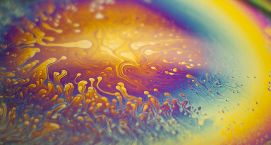 A horizontal soap bubble film drains towards its center, while ...